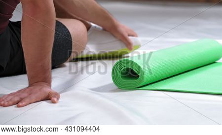 Relaxing Athletic Man Sitting On The Floor Next To Unwinded Roll Mat ...