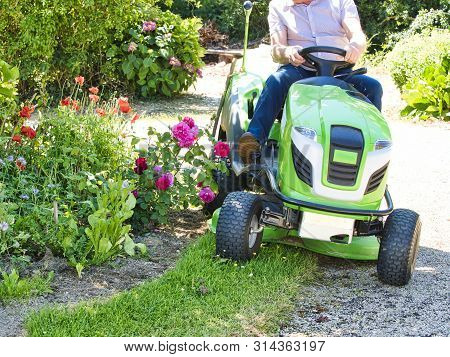 Senior Man 75 Old Years Driving A Tractor Lawn Mower In Garden With ...
