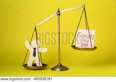 Gender Pay Gap. Wooden Figure Of Man And Paper Note On Scales Against ...