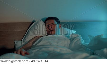 Young Man Under Blanket Sleeping On Bed In Evening. Sleepy Male Yawns ...