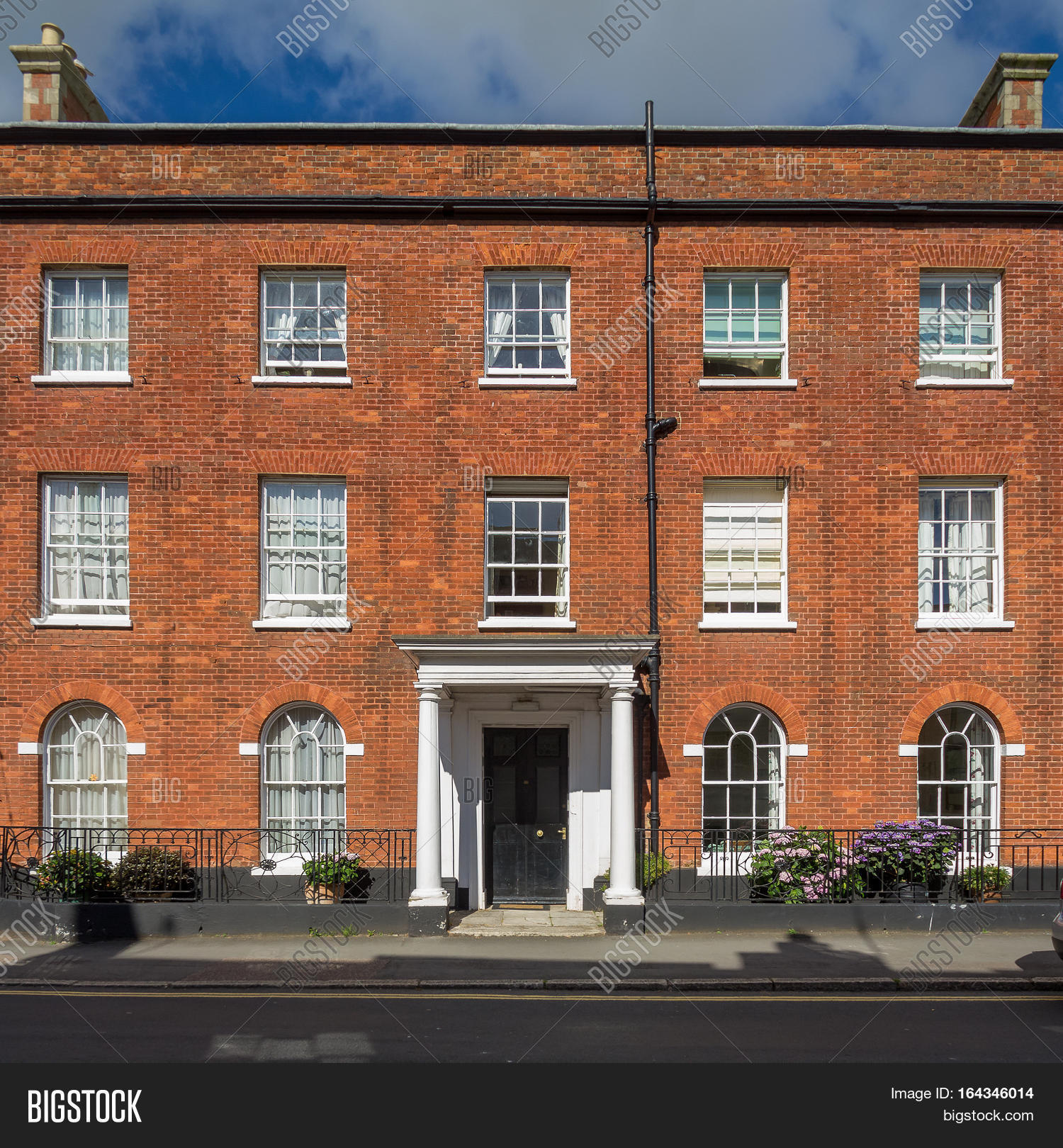 facade of the three-storey red brick building. White porch. Devon. UK ...